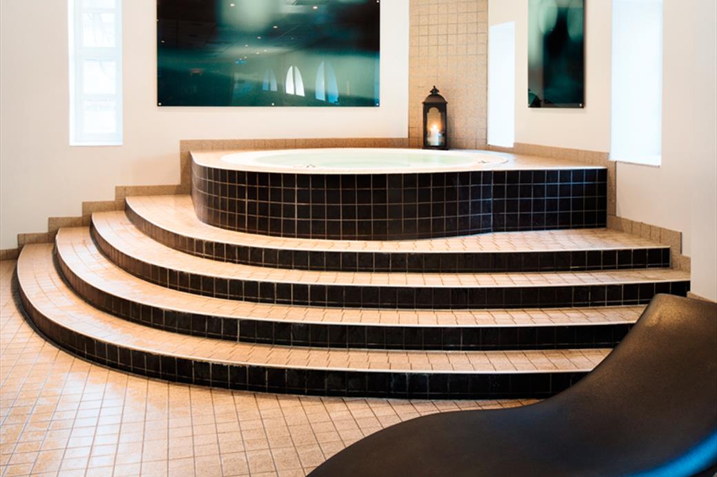 En jacuzzi med elegant, sort stol og flislagt gulv.
